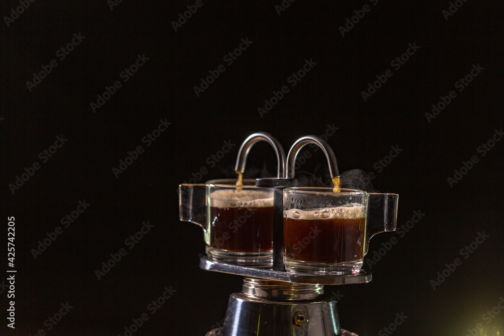 Heat vapor emitted from the coffee machine..Two black coffeemakers in a ...