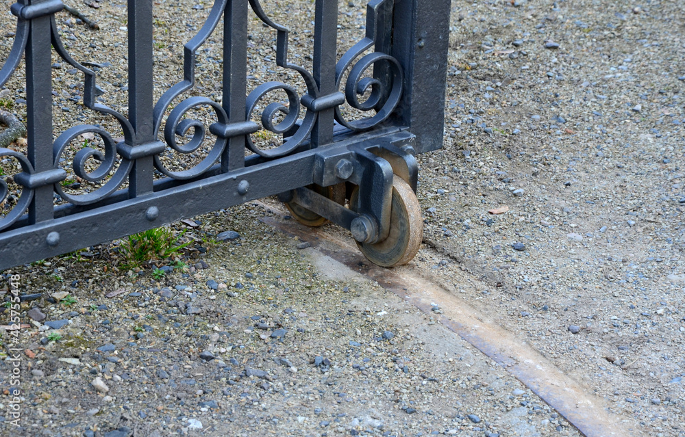thanks to its weight, a heavy steel gate hangs in hinges and crosses ...