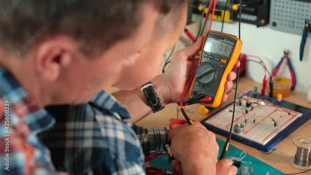 Dad and son are checking electrical equipment. They test the ...