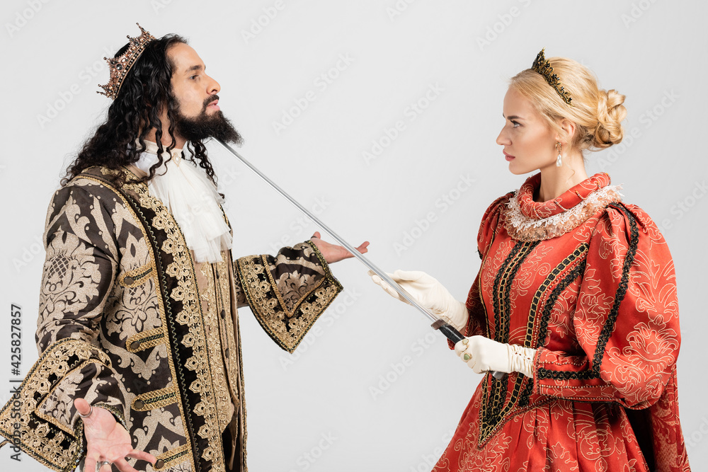 blonde queen holding sword near neck of hispanic king in medieval ...