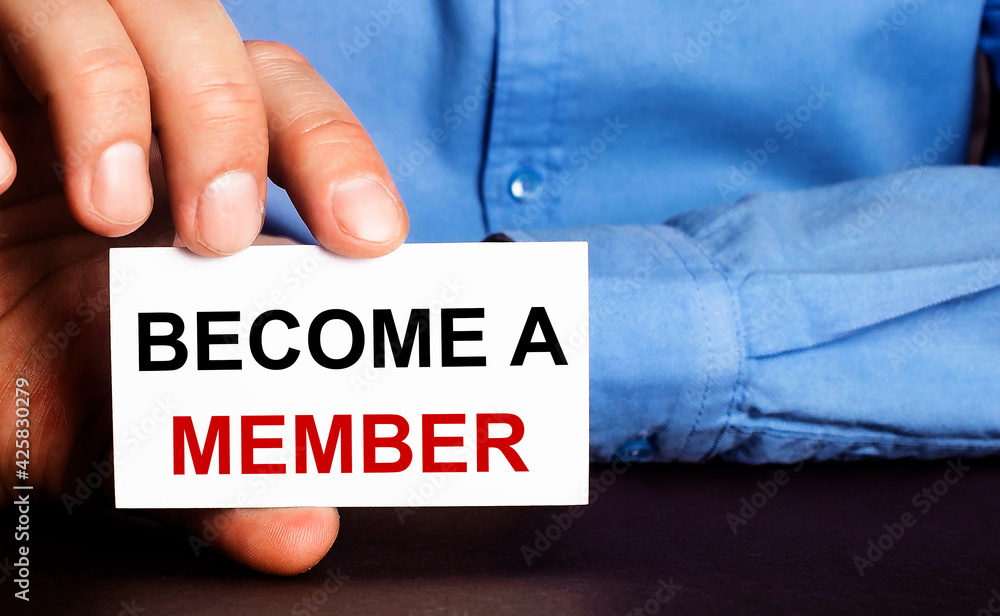 BECOME A MEMBER is written on a white business card in a man's hand ...