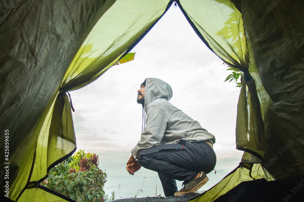 Hombre sentado acampando en una carpa o tienda de campaña viendo el ...