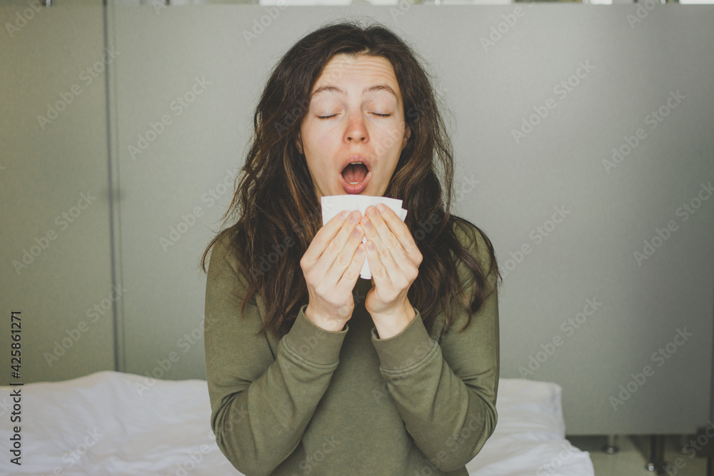 Sick young woman sneeze into paper napkin, blowing running nose ...