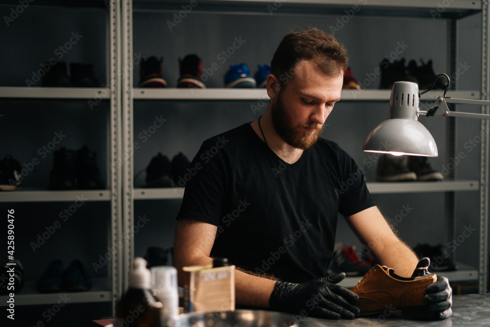 Portrait of shoemaker shoemaker wearing black gloves inserts wooden ...