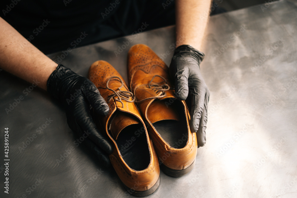 Close-up top view of hands of shoemaker shoemaker in black gloves ...