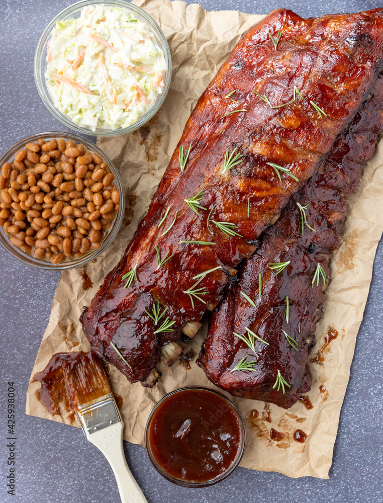 Overhead image of two racks of smoked pork BBQ ribs covered in BBQ ...