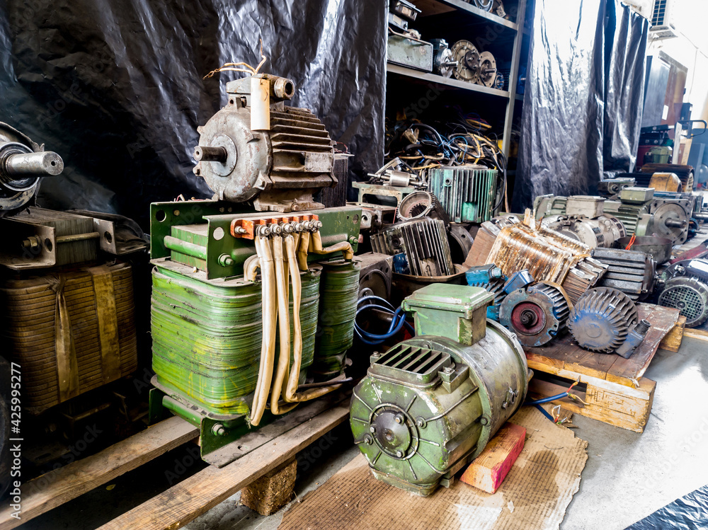 Warehouse of old non-working electric motors on racks and on the floor ...