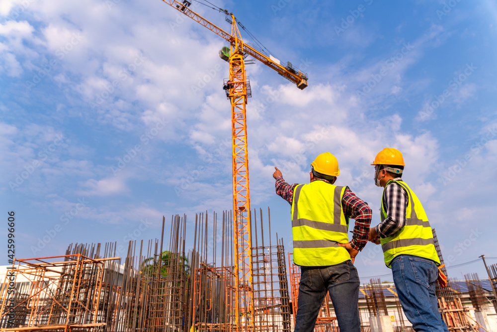 Construction engineers and architect supervising progress of building ...