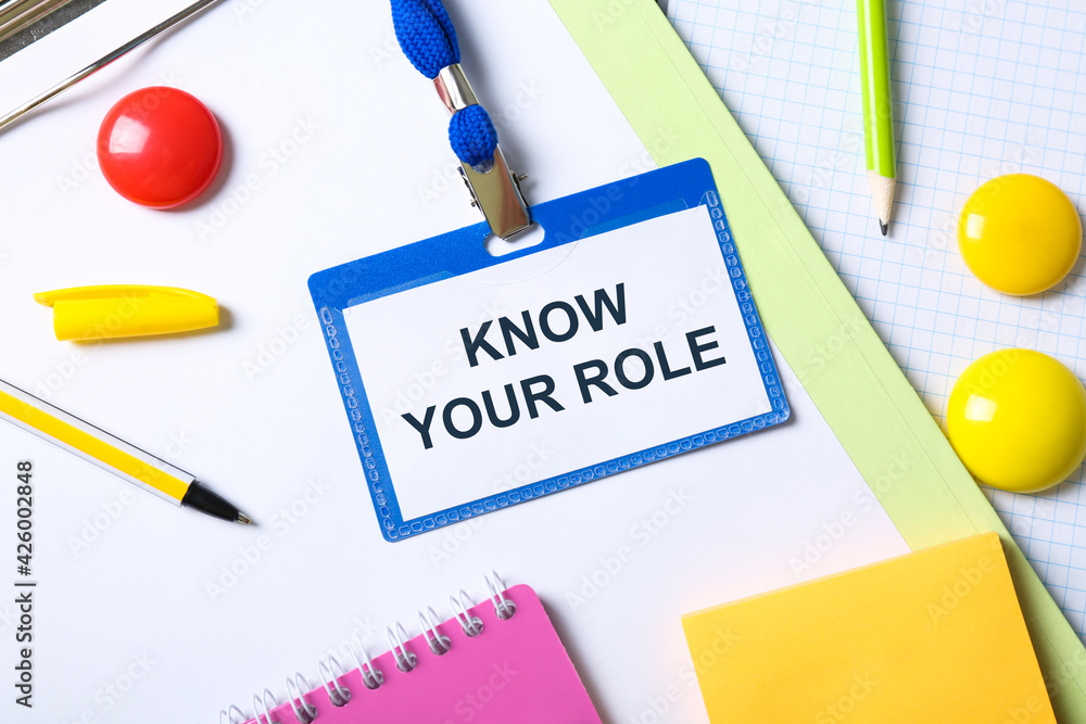 Badge with phrase Know Your Role and stationery on clipboard, flat lay ...