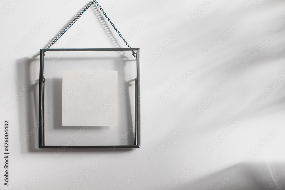 Mockup of black metallic square frame hanging on a chain against a ...