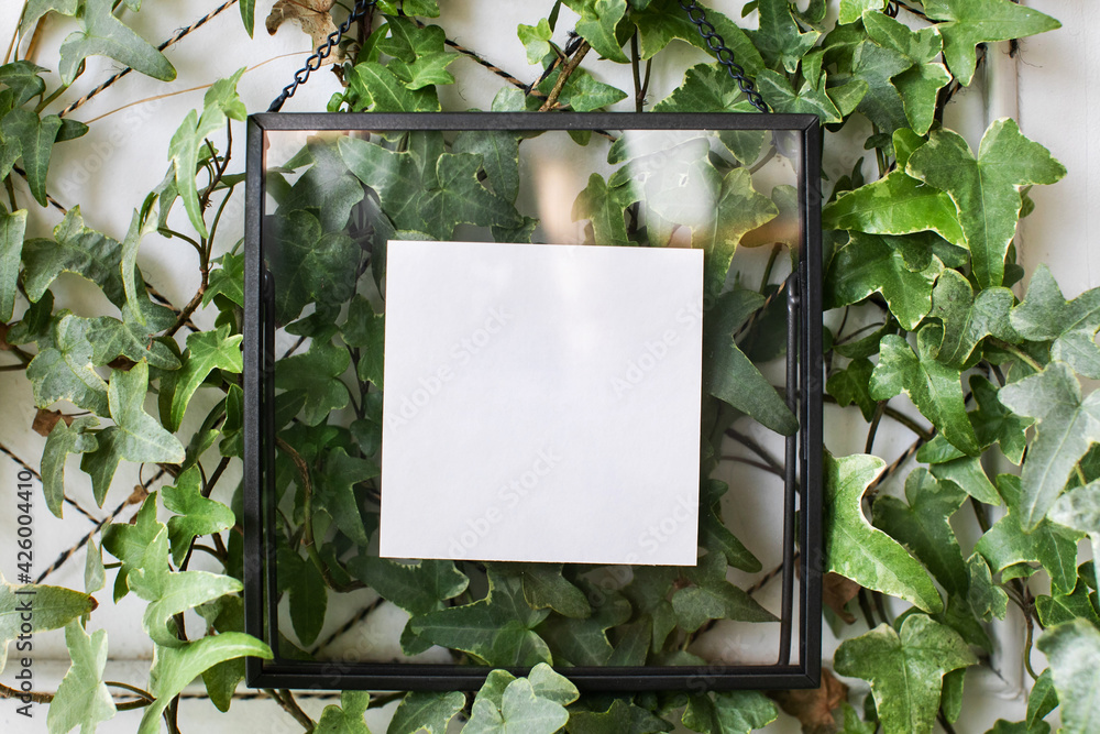 Mockup of black metallic square frame hanging on a chain against the ...