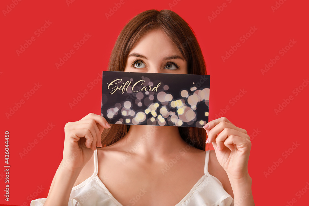 Beautiful young woman with gift card on color background Stock Photo | Adobe Stock
