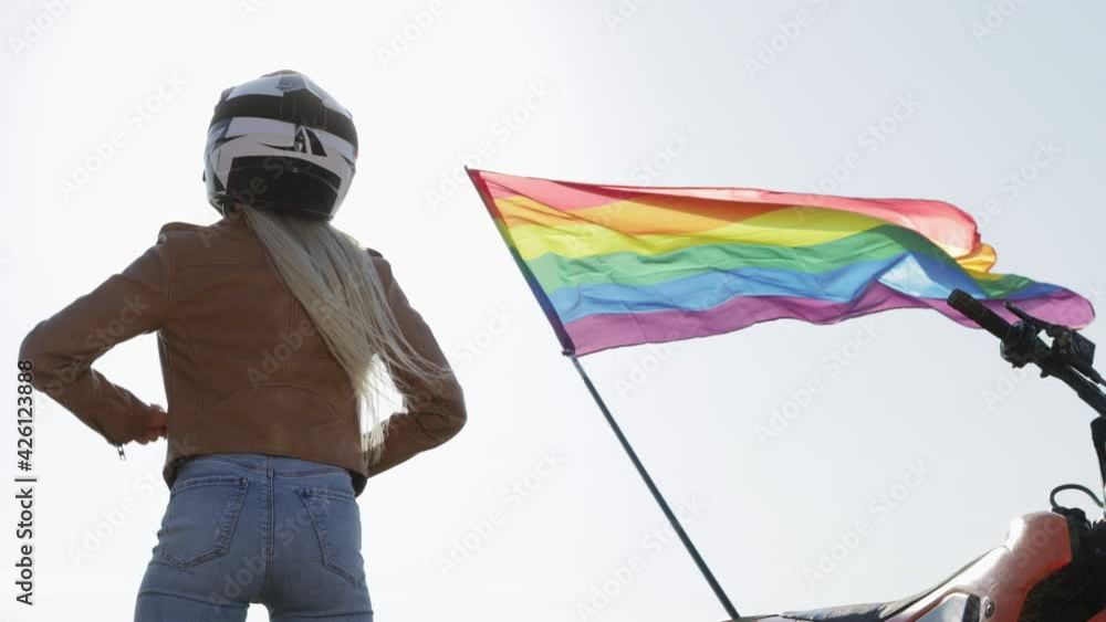 A biker girl stands in a protective helmet with her back to the camera ...