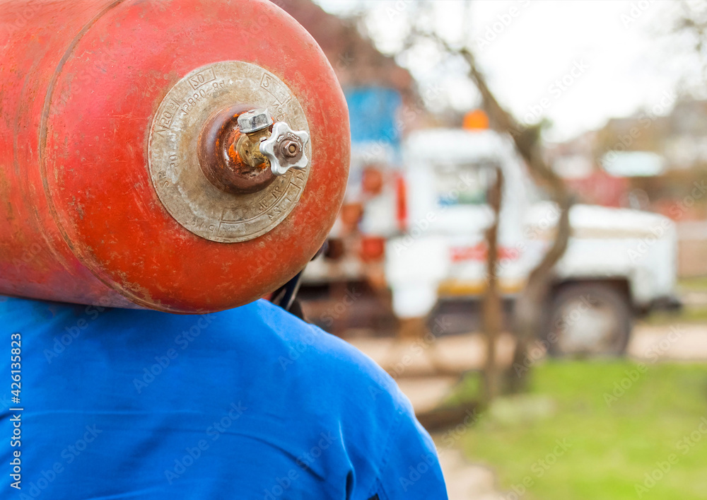 A male industrial worker walks with a gas cylinder to a gas car ...