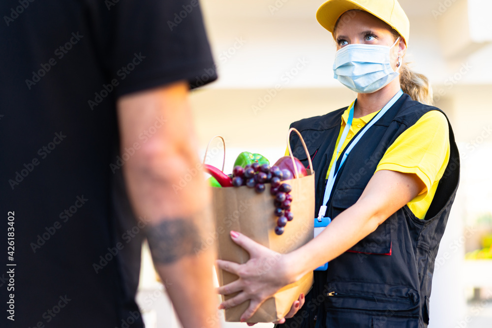 Handsome food delivery service woman in yellow shirt holding fresh ...