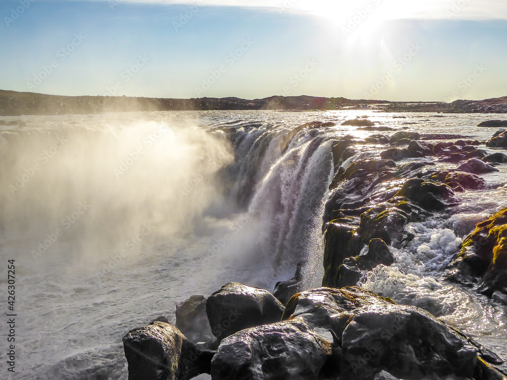 A waterfall splashing a lot of water drops around, caught on a sunny ...