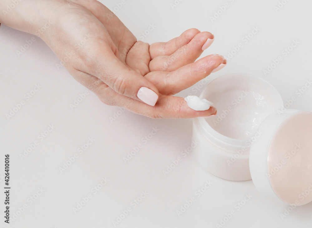Female hand above whote background with opened lotion cream for ...