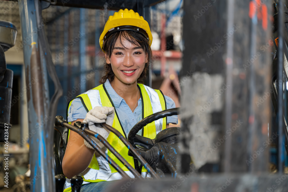 A female engineer is controlling a forklift in a spare parts factory. A ...