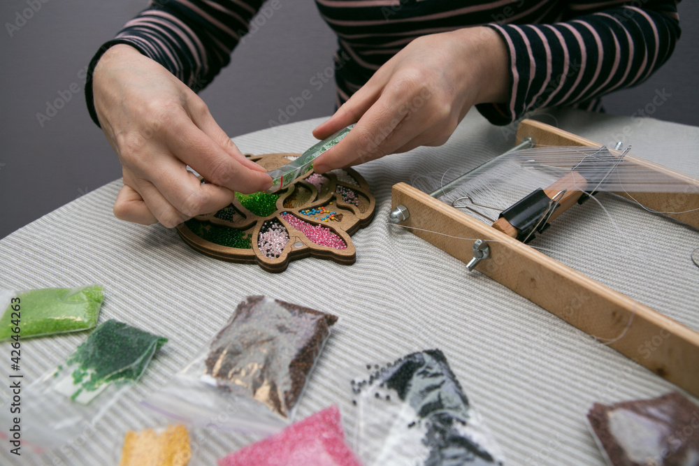 Foto de Weaving from beads. Close-up - a woman's hands are stringing ...