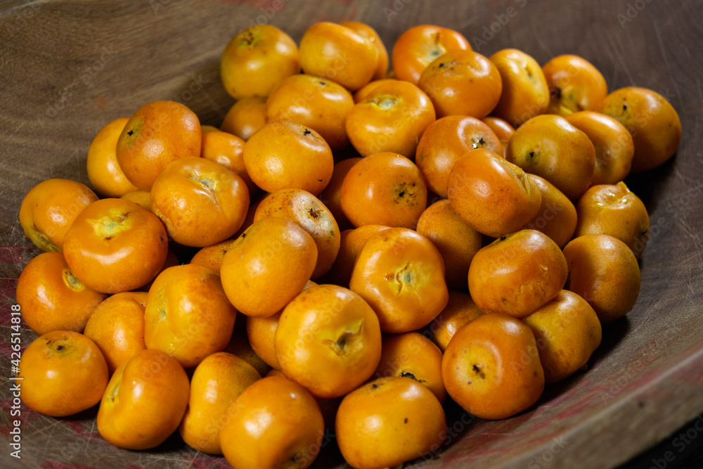 A wooden bowl filled with Butia Capitata, the palm fruit, commonly ...