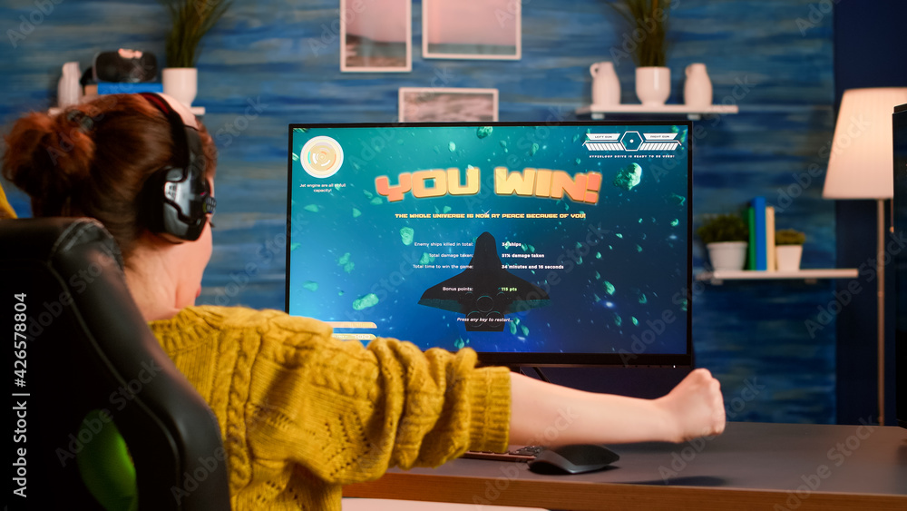 Back view of happy pro gamer winning space shooter game, raising hand ...