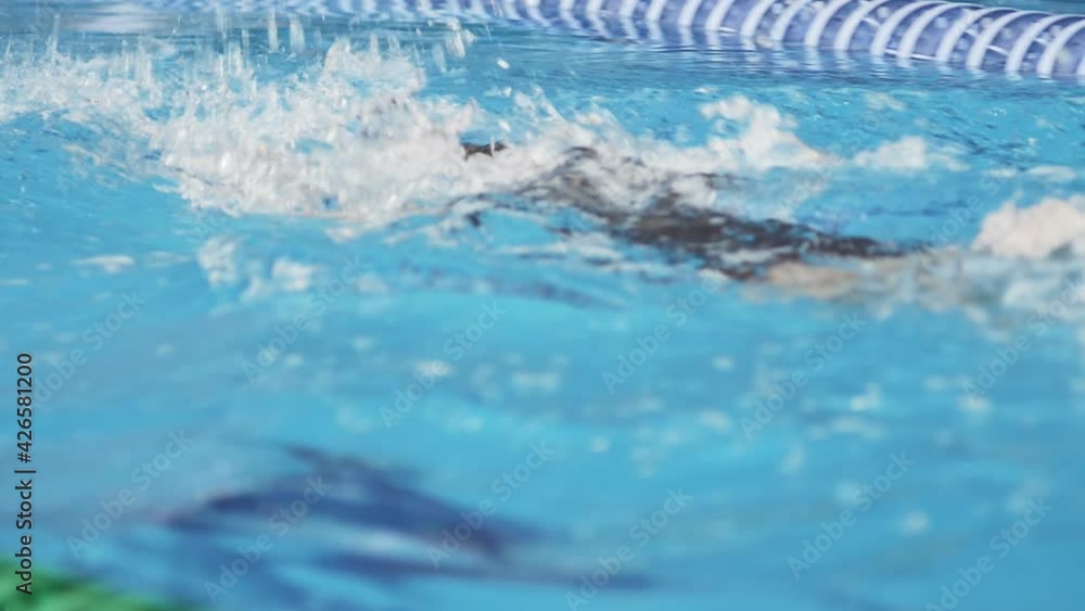 slow motion close-up a teenage swimmer swims in the pool at a swimming ...
