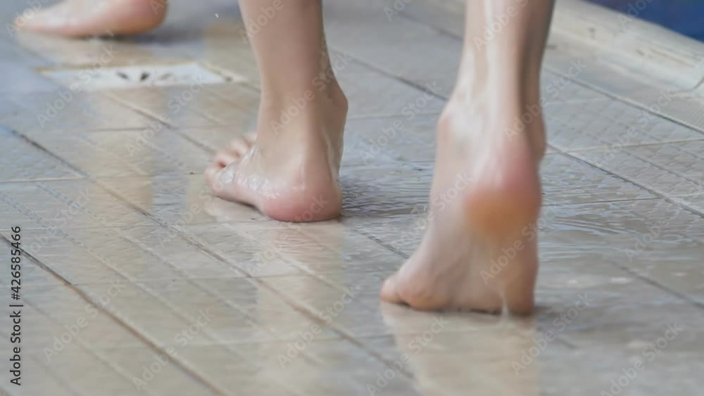close-up of the feet of children in the pool, who step on the tiled ...