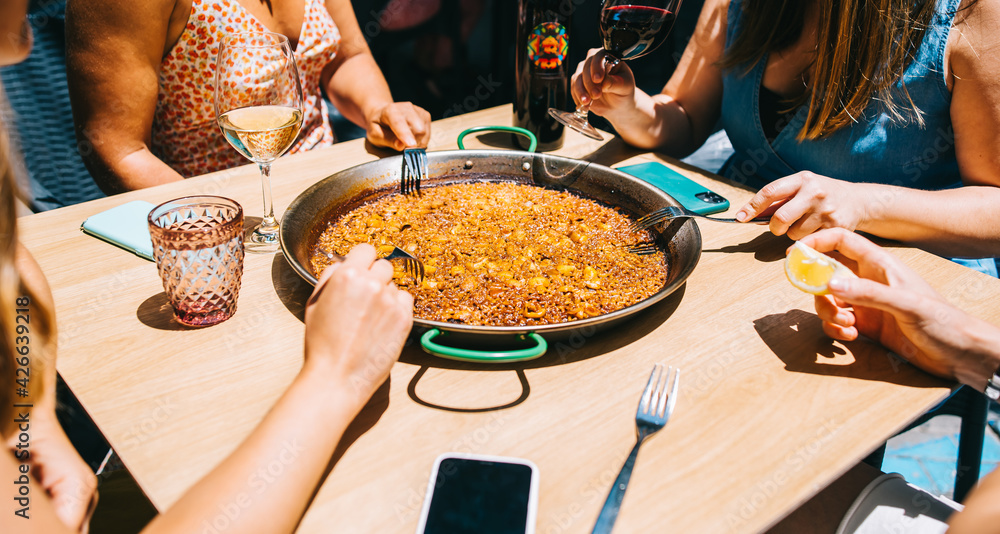 Time to eat paella. Several hands with cutlery begin to eat paella at a ...