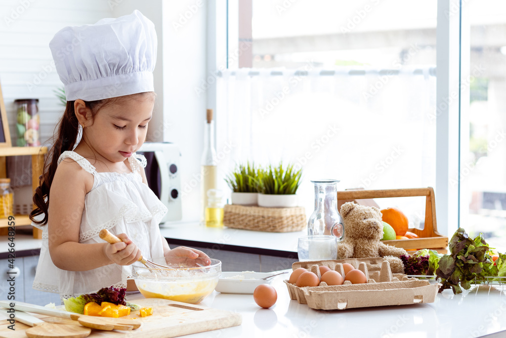 Little Caucasian girl wearing white chef hat cooking in kitchen. Child ...