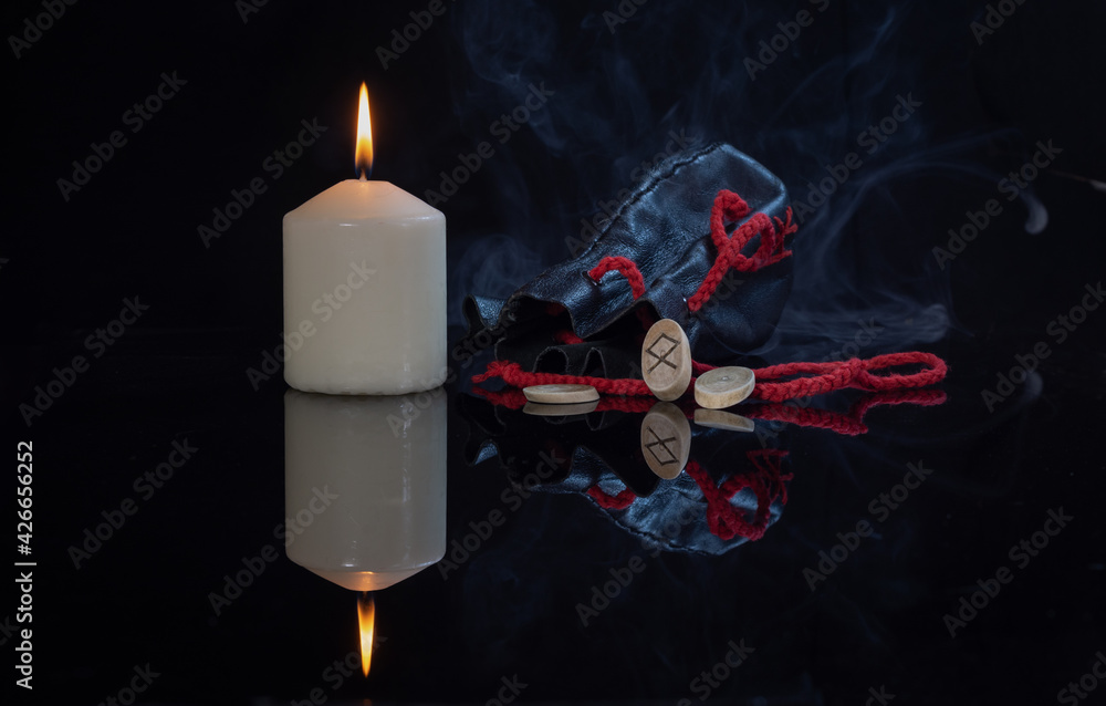 Odal rune, a burning candle, an old leather bag for Scandinavian runes ...