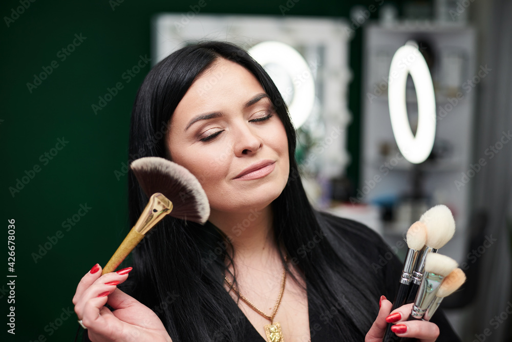 Portrait of make-up artist at workplace in beauty studio, holding ...