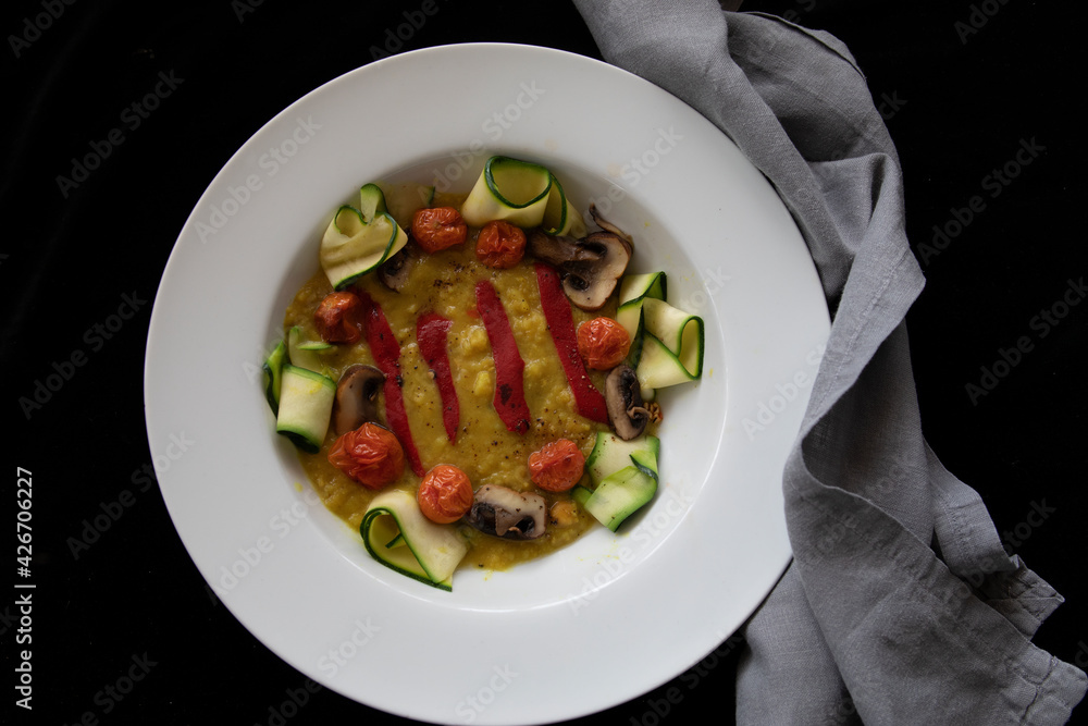 VEGAN DINING, WHITE DISH OF BEAN SOUP GARNISHED WITH ROASTED RED PEPPER ...