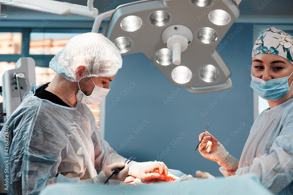 Doctors performing abdominoplasty surgery in the hospital. Focus on ...