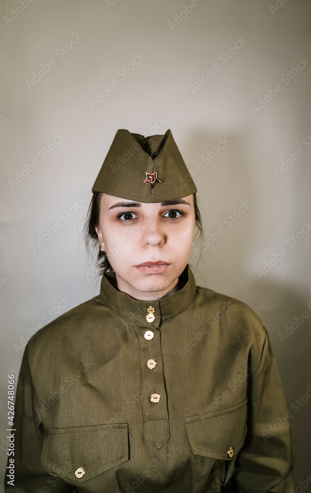 Portrait of young woman in uniform on background of gray wall. Female ...