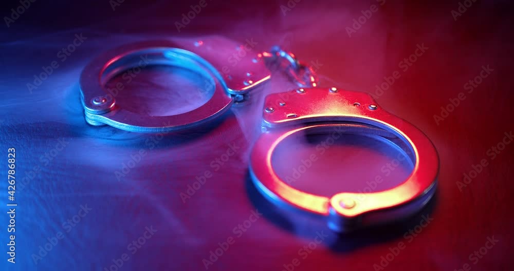 Pair of handcuffs used by law enforcement to arrest criminals, lit in ...