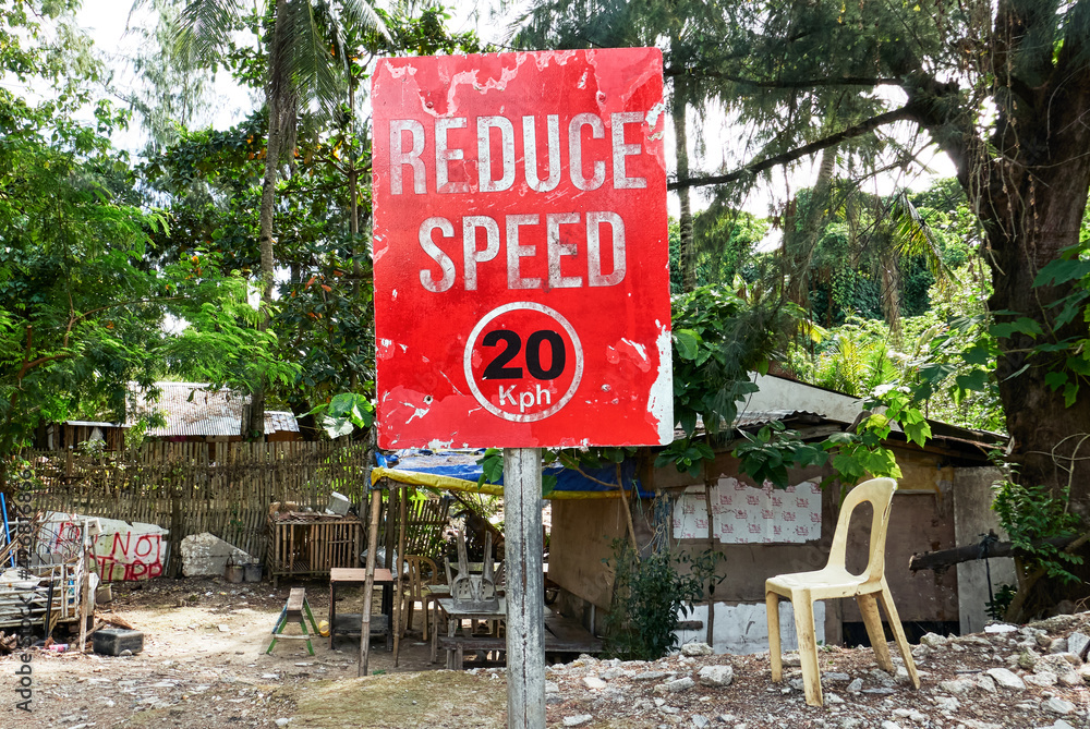 Bright red colored Reduce Speed road signage standing in front of a ...