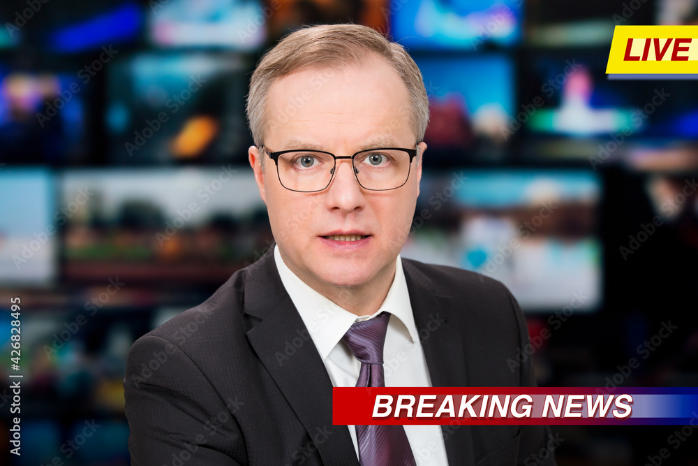 An anchorman reporting live breaking news sitting in Tv studio ...
