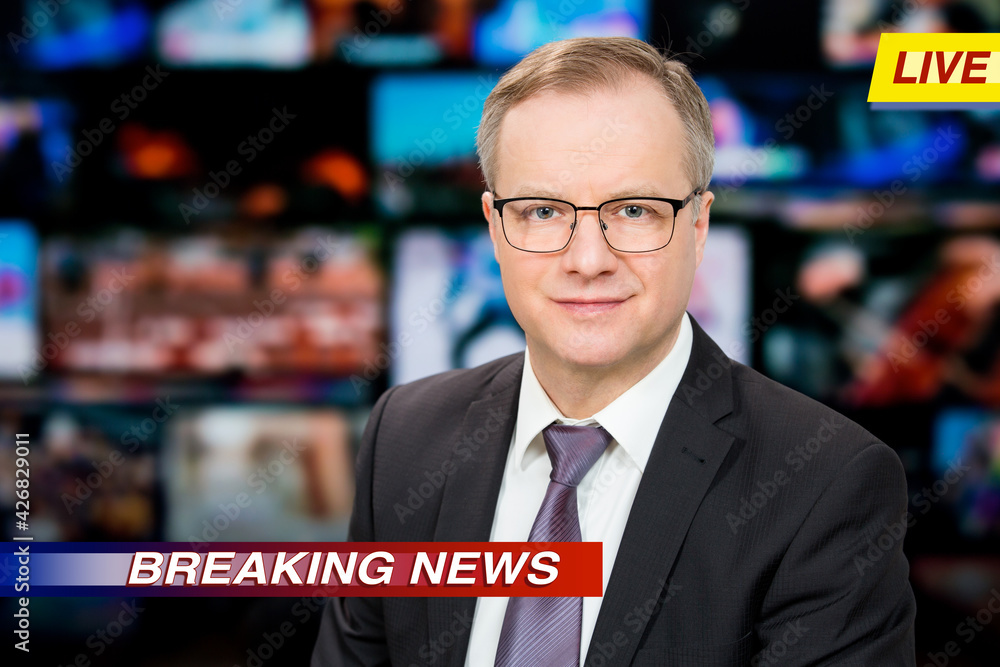 An anchorman reporting live breaking news sitting in Tv studio ...