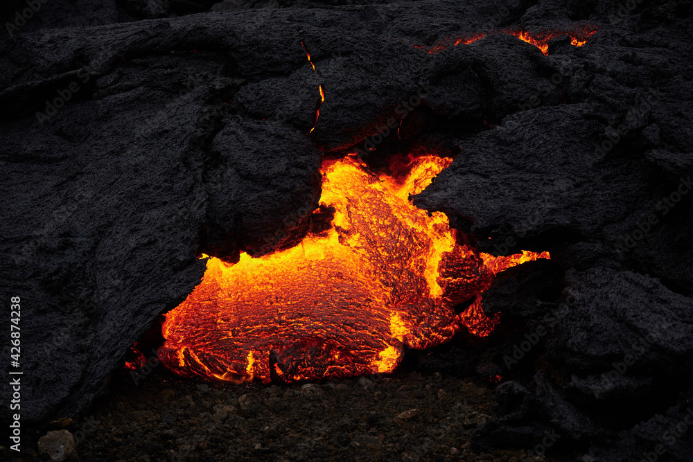 Magma or melted lava flowing through hardened lava glowing from heat ...