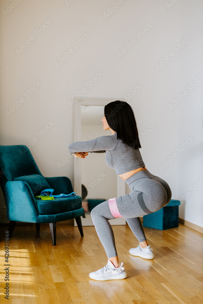 Attractive fitness woman doing squat workout at home. Woman with strong ...