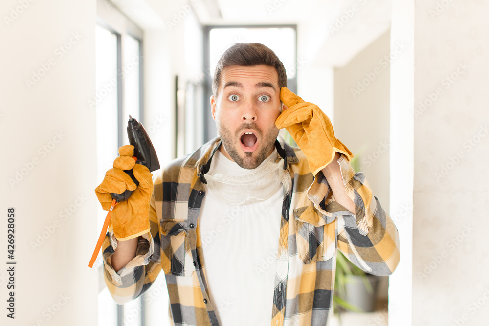 handyman looking surprised, open-mouthed, shocked, realizing a new ...