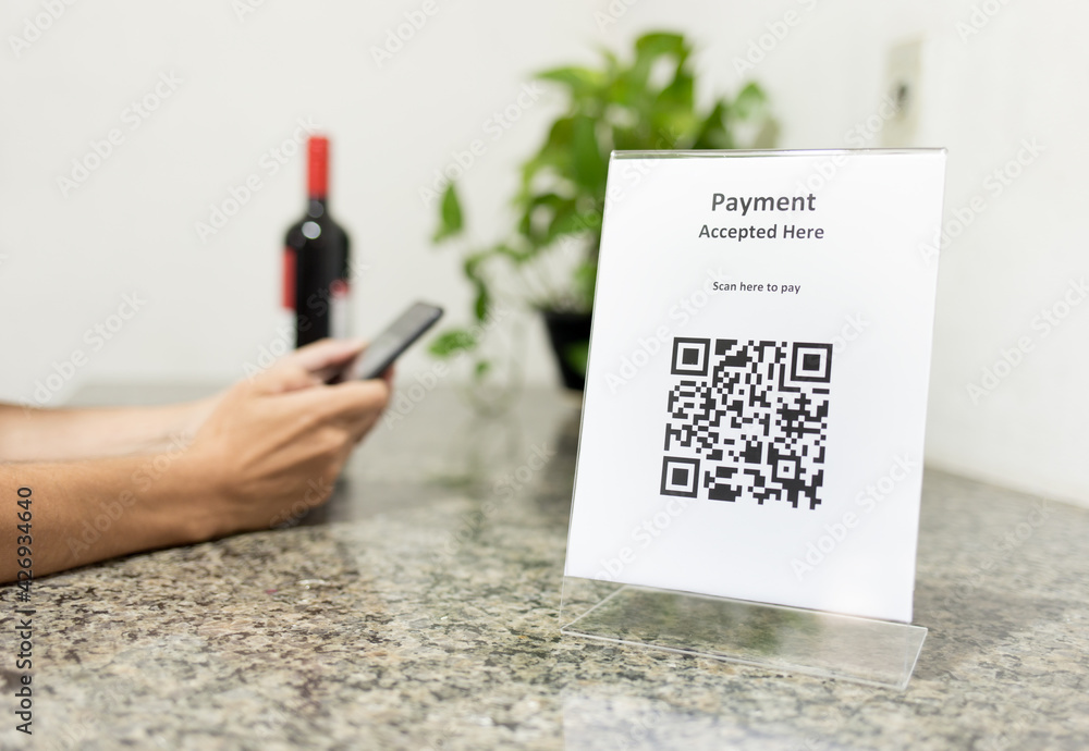 Sign with a QR Code to generate payment in a bar and a hand holding a ...