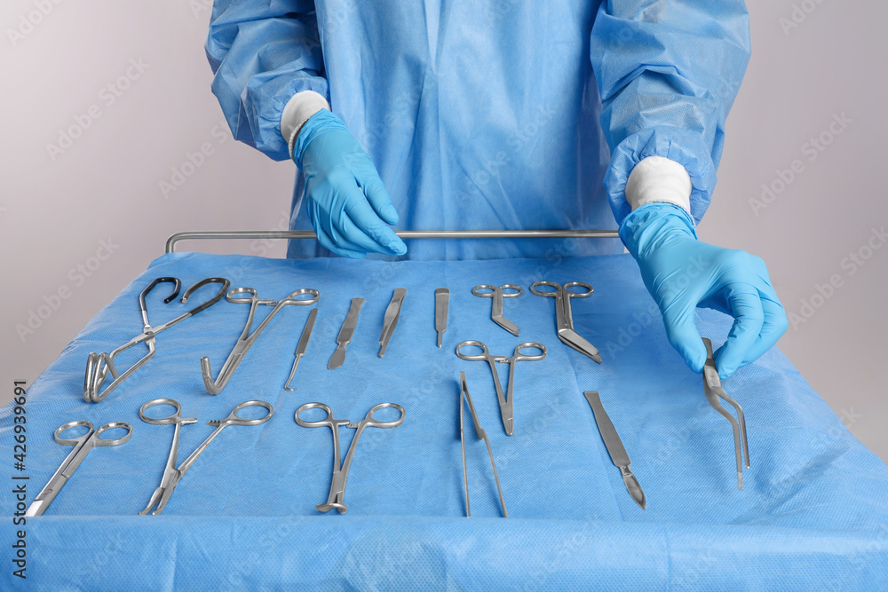 Doctor holding medical forceps near table with different surgical ...