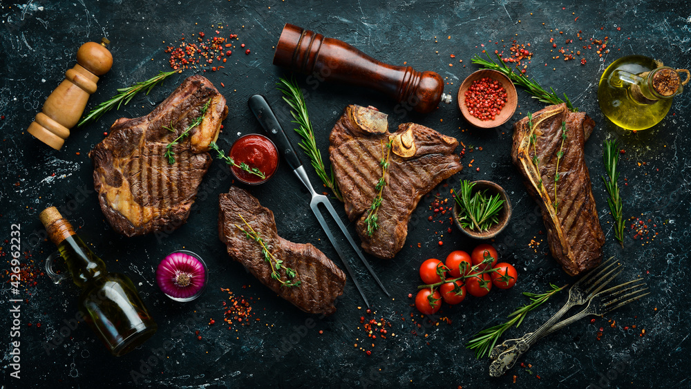 Steak menu. Juicy grilled steaks on a black stone background: t-bone ...