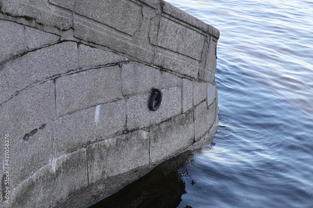 Cast iron ring in the granite embankment for mooring ships. Cold bluish ...