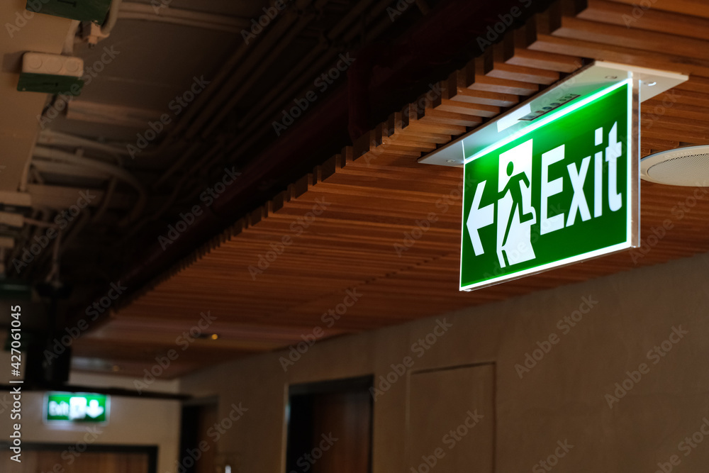 Green fire escape sign hang on hotel ceiling. Green exit sign. LED ...