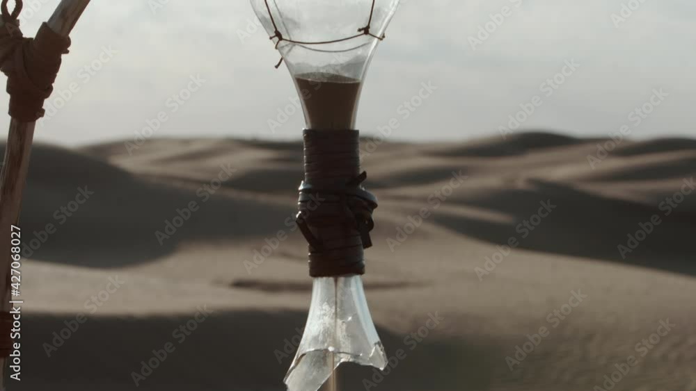 A stream of sand spilling out of a broken hourglass. Still life shot ...