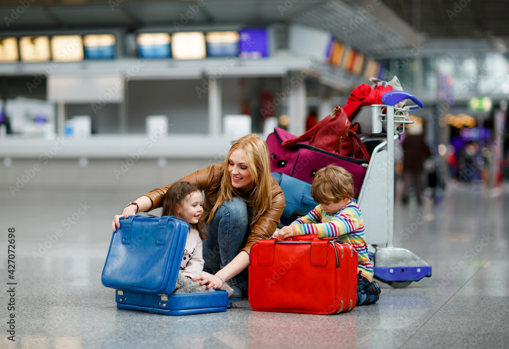 Two tired little kids, boy and girl, siblings and mother at the airport ...