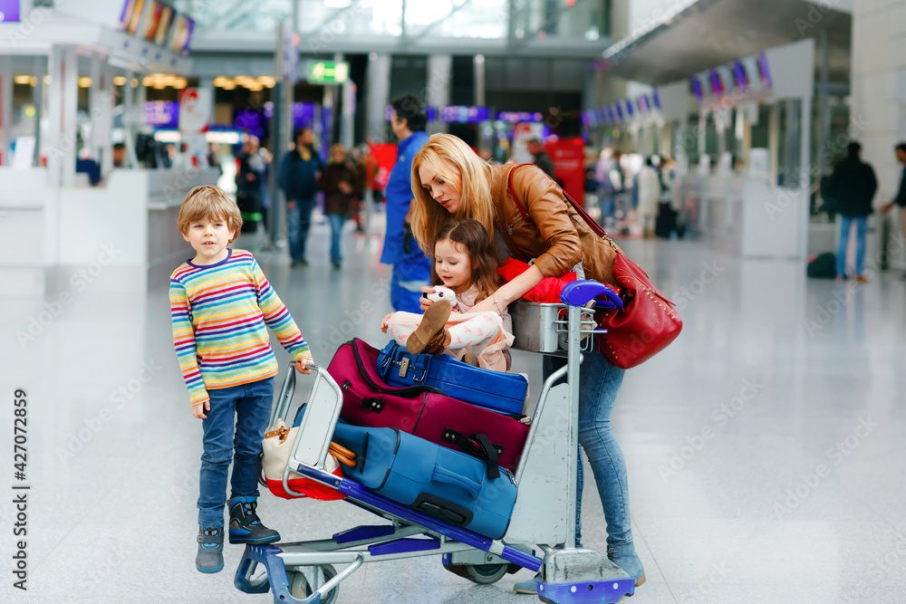 Two little kids, boy and girl, siblings and mother at the airport ...