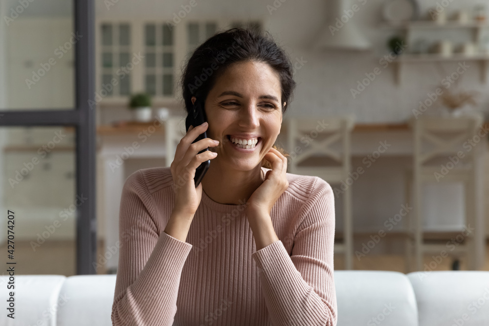 Cheerful millennial latin female with bright white smile sit on couch ...
